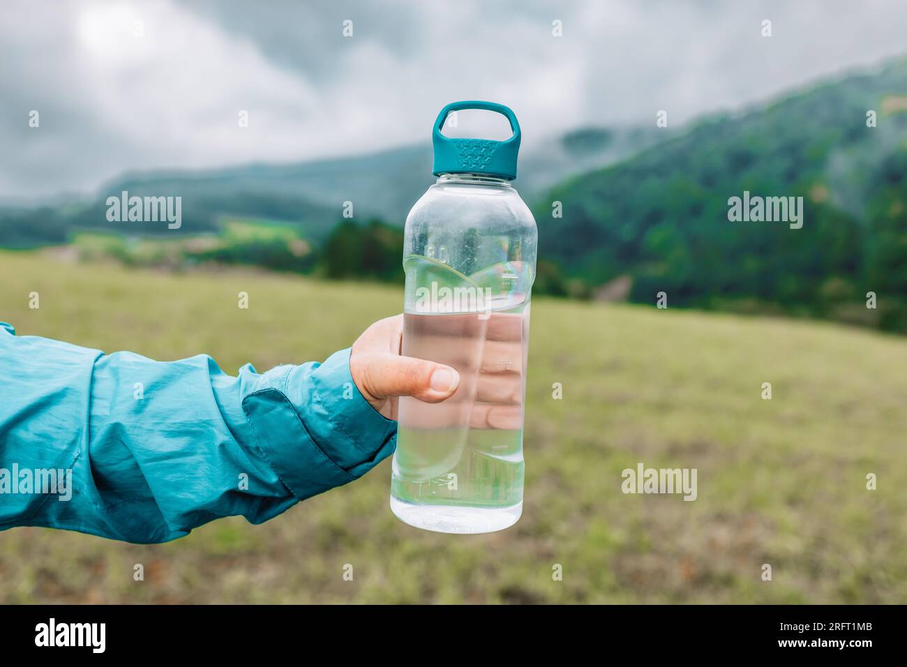 caucasian 50s blonde girl drinking water from plastic bottle. Mountain ...