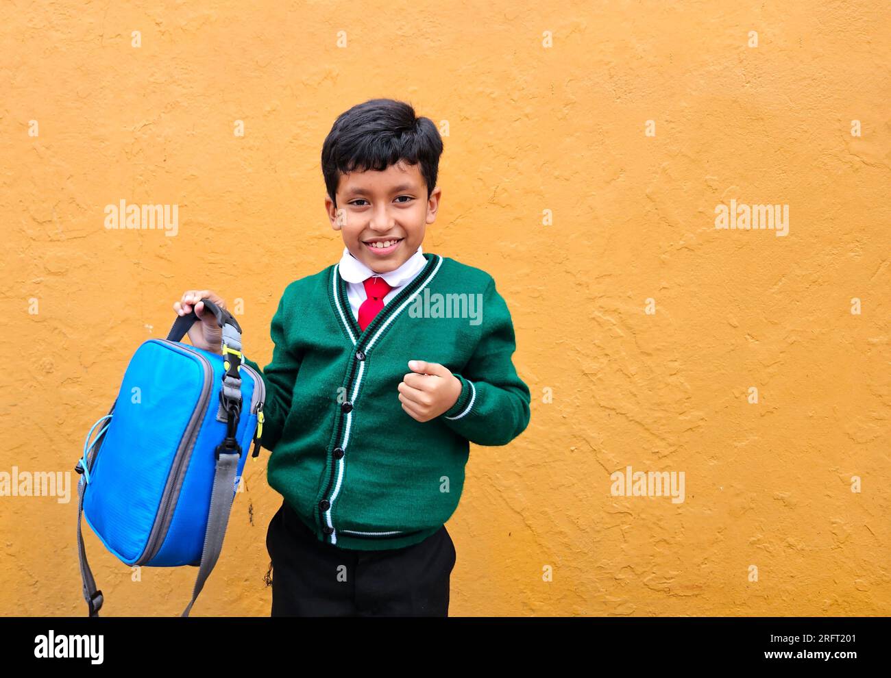 Dark-haired 9-year-old Latino boy in a school uniform shows off his new ...