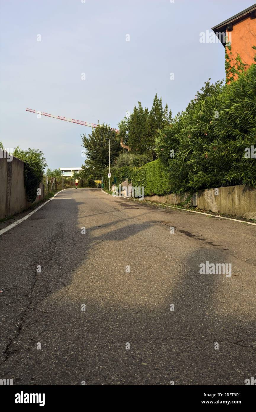 Road on a hill bordered by houses and an embankment Stock Photo - Alamy