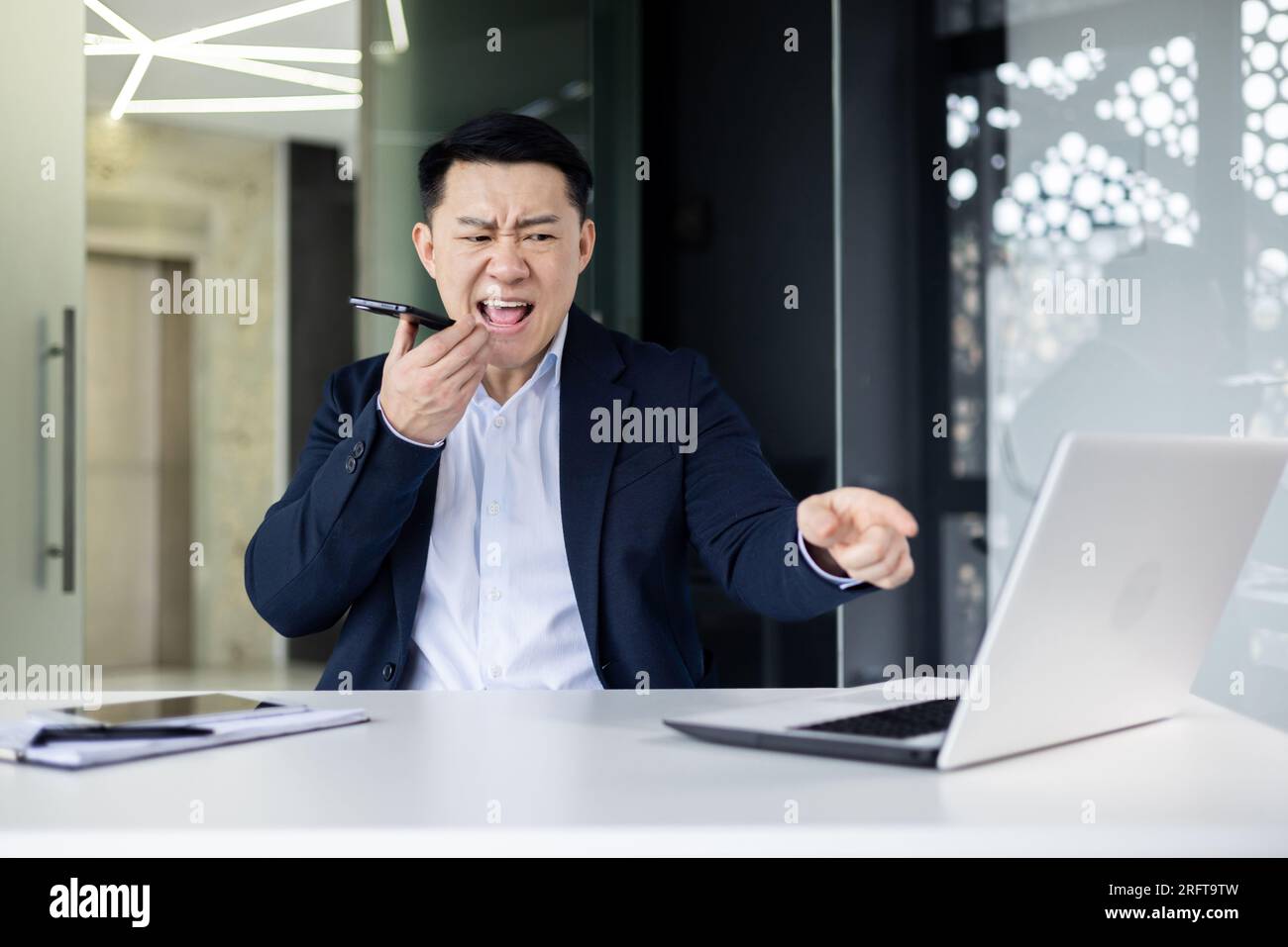 Angry angry asian boss talking on the phone, businessman at workplace ...