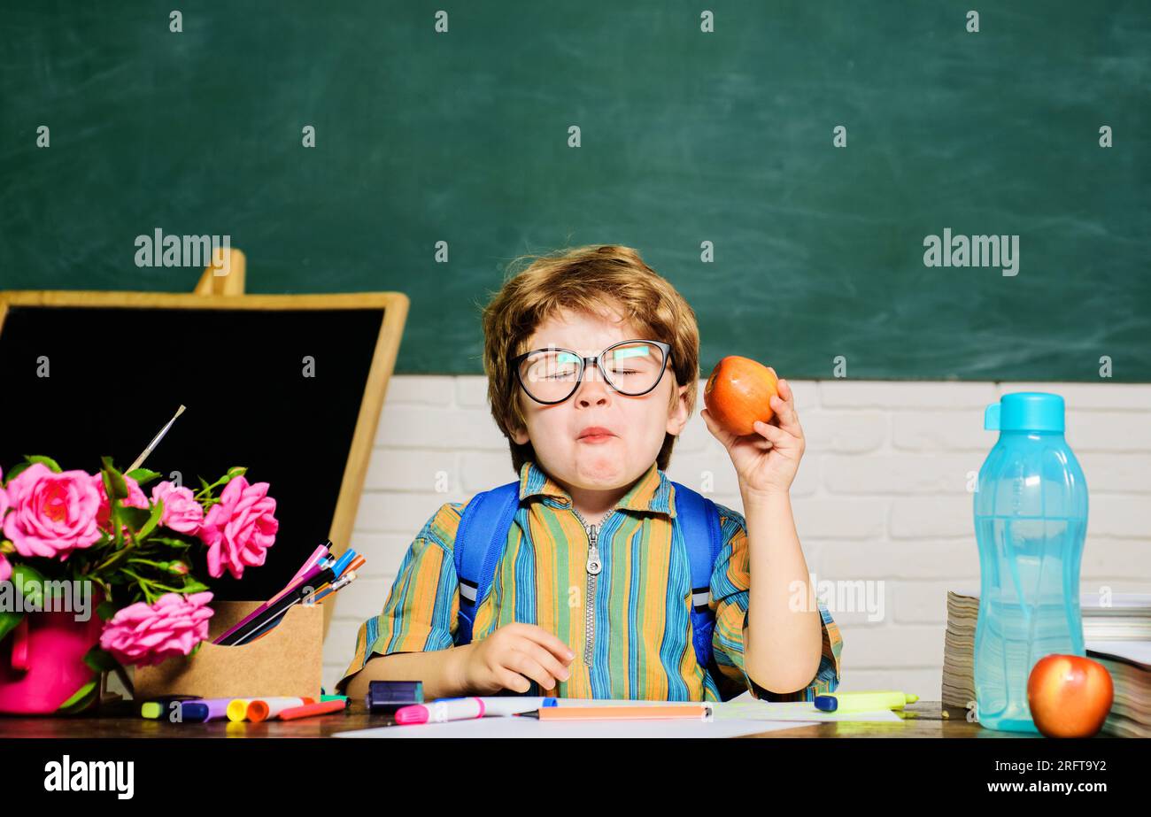 Little schoolboy in glasses eating apple at lunch time. Healthy ...