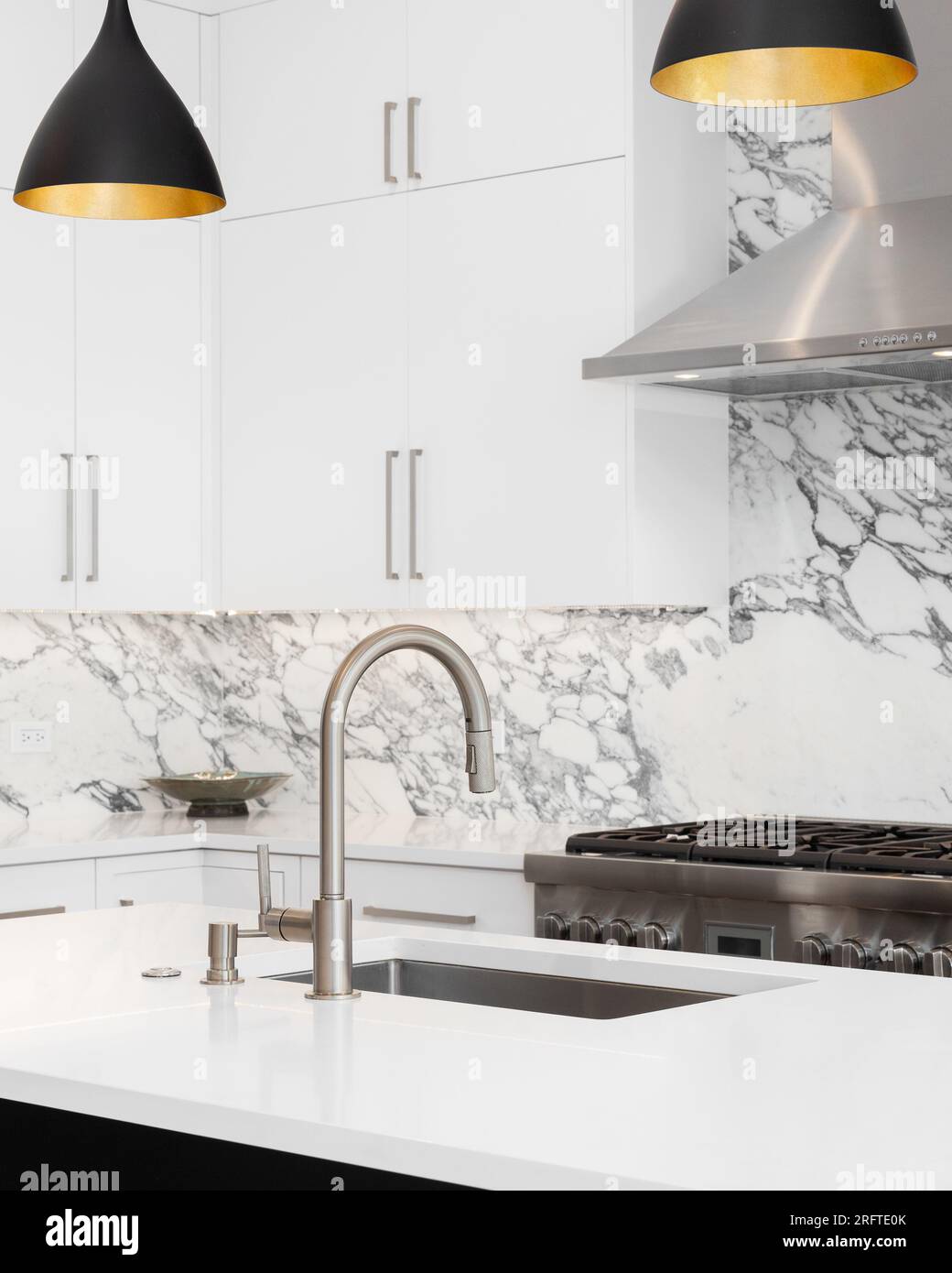 A kitchen detail with white cabinets, modern light fixtures hanging ...