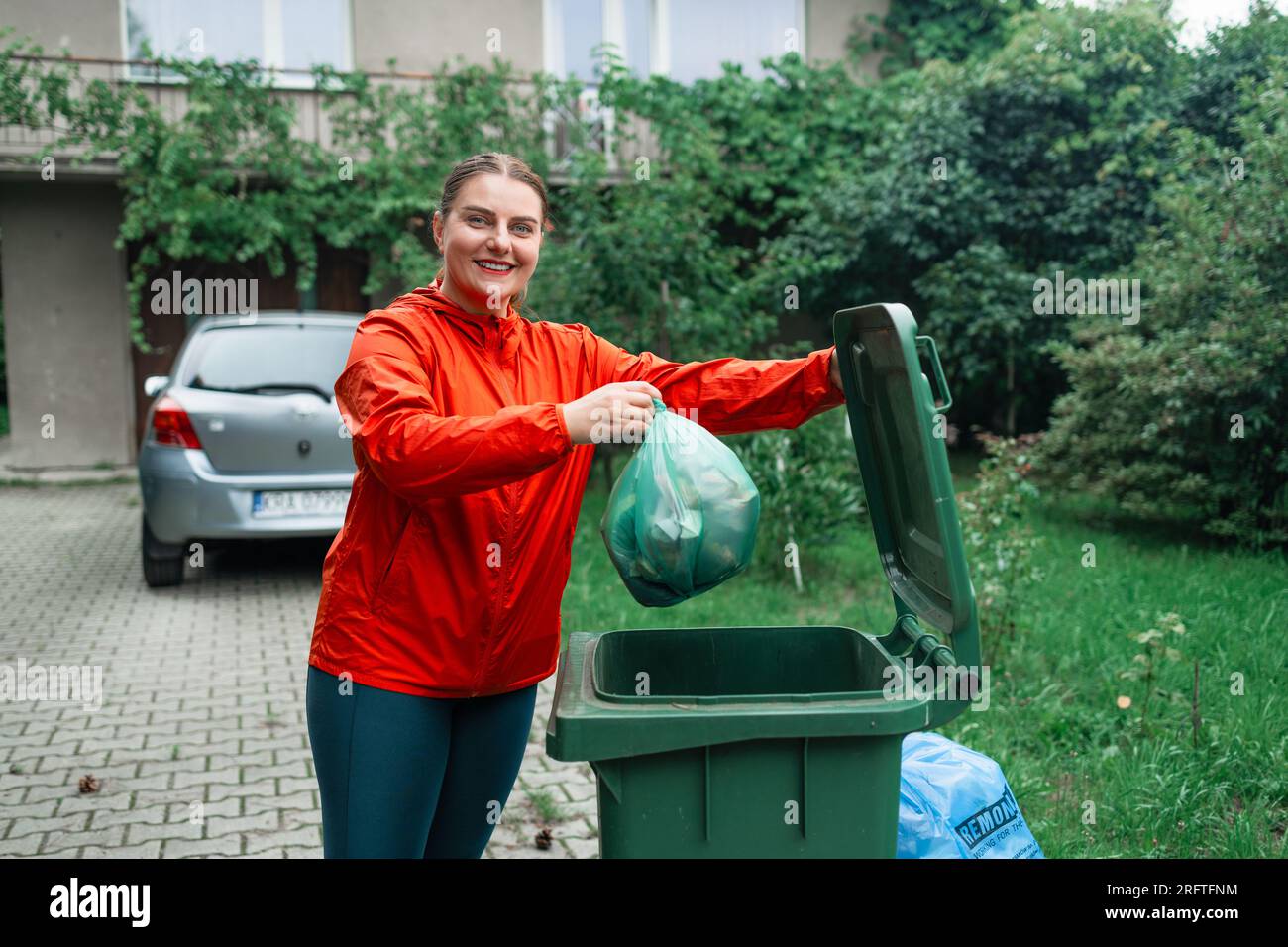 Caucasian woman sorting garbage, throwing a used bag with trash in a ...