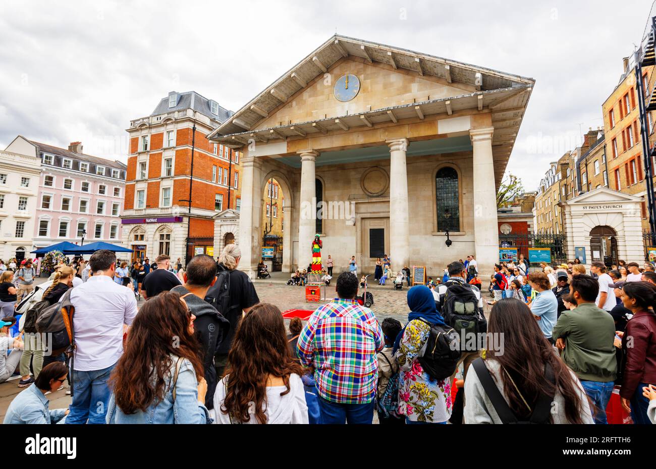 Spectators watch and enjoy a traditional street performer in the piazza ...