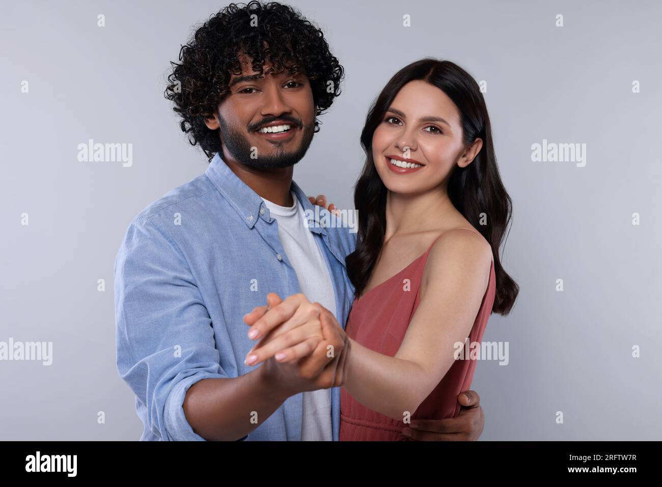 International dating. Happy couple dancing on light grey background ...