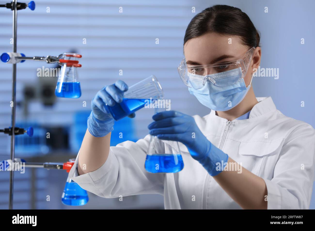 Scientist pouring sample into flask in laboratory Stock Photo - Alamy