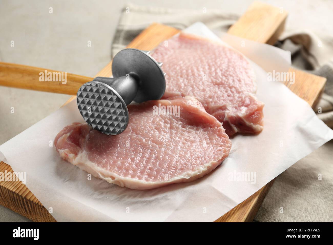 Cooking schnitzel. Raw pork chops and meat mallet on grey table ...