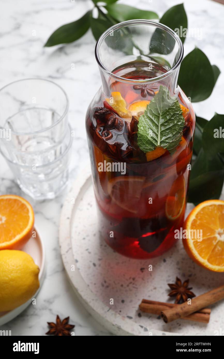 Delicious punch drink in bottle, spices and citrus fruits on white ...