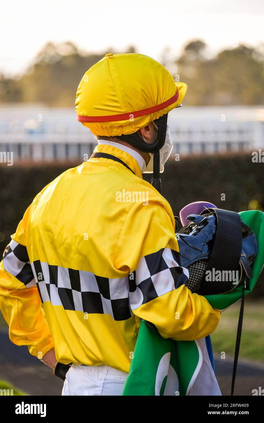 Jockey wearing yellow silk standing in the paddock after winning the ...