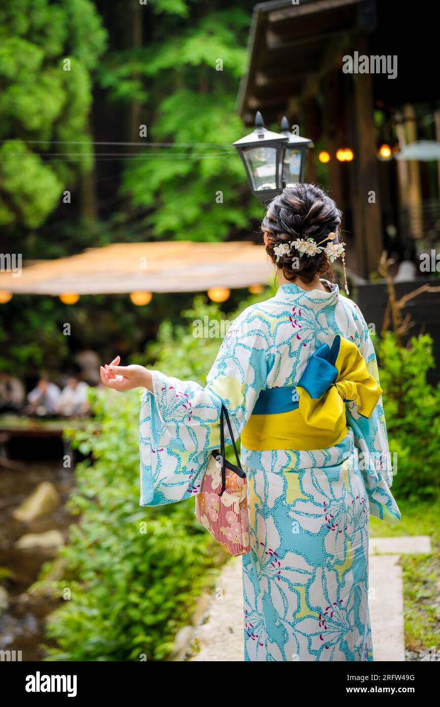 Back view of two women wearing Japanese yukata summer kimono walking on ...