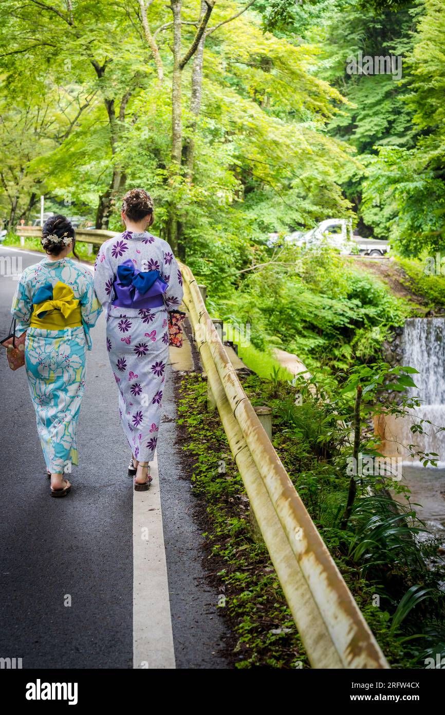Back view of two women wearing Japanese yukata summer kimono walking on ...
