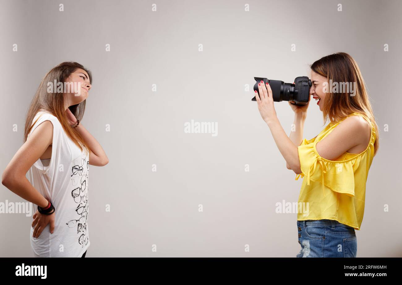 young photographer smiles at her beautiful, younger model, guiding her ...