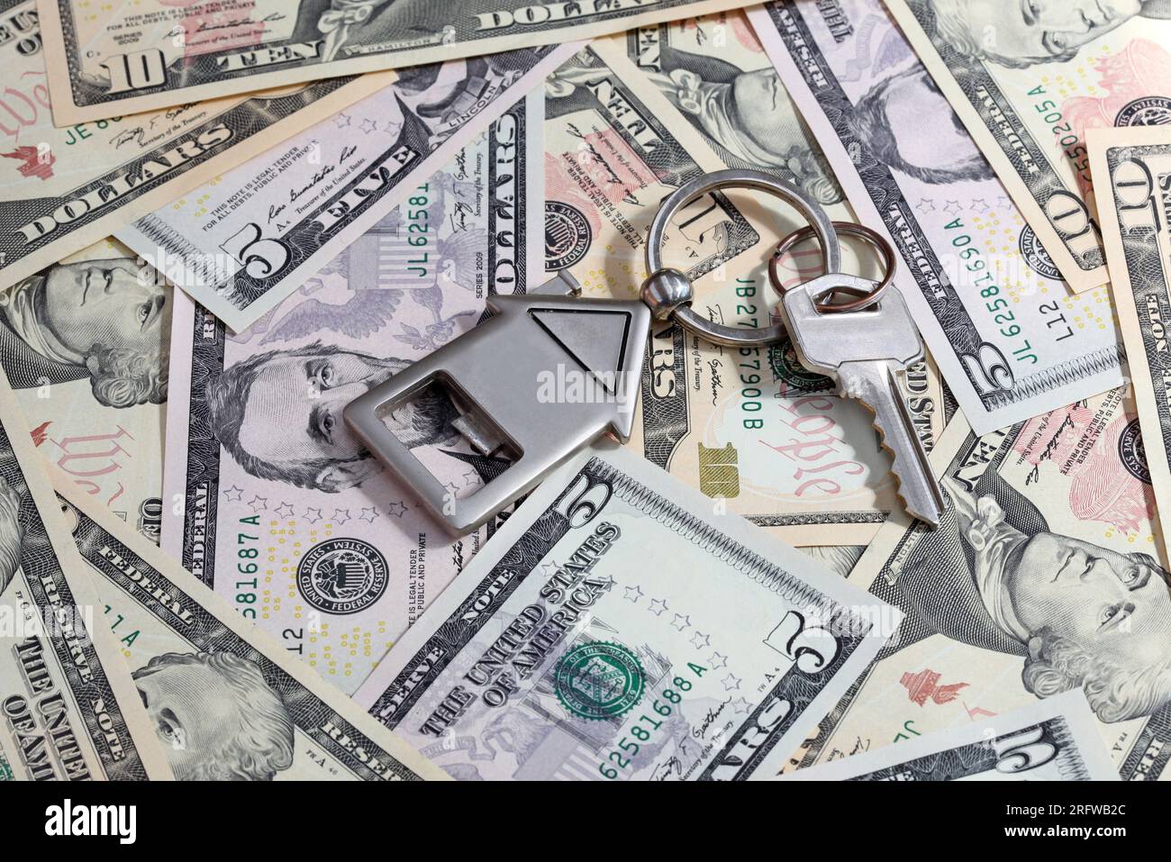 A house key and keyring on top of various US dollar notes. Only partial ...