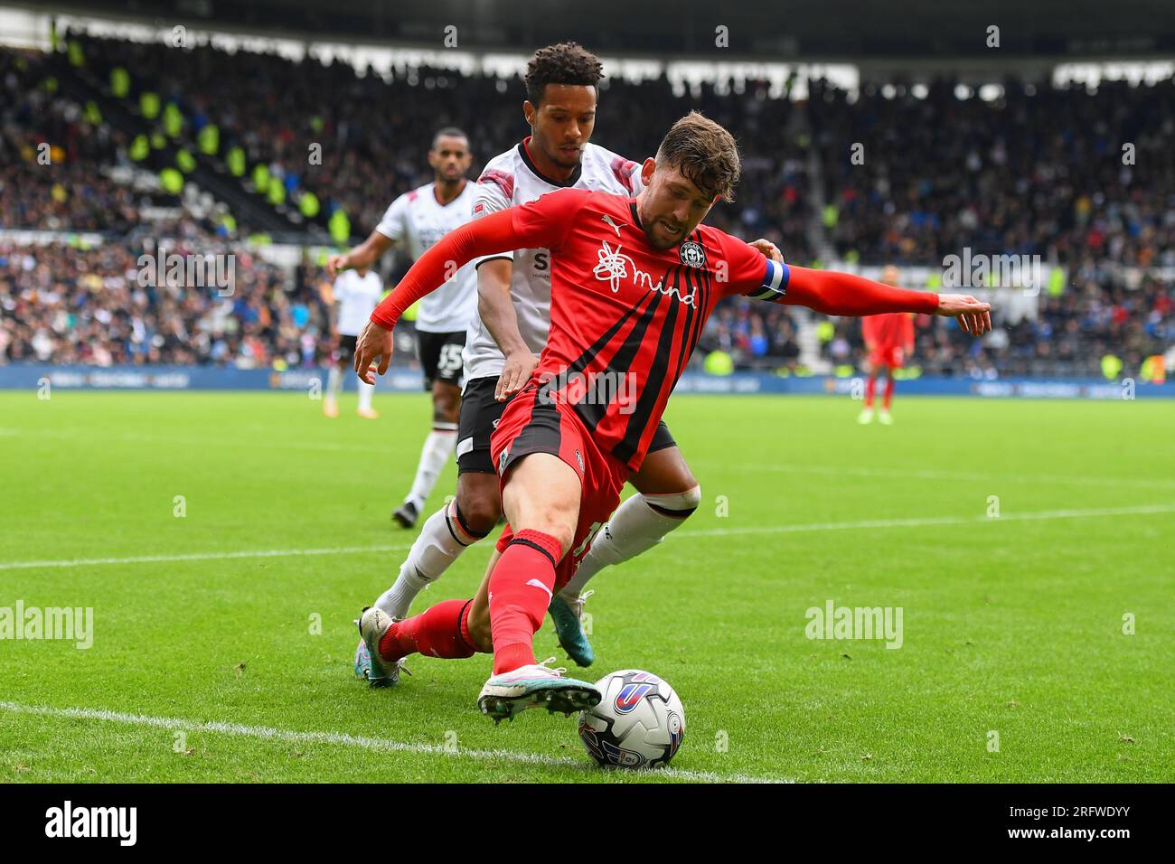 Callum Lang of Wigan Athletic shields the ball from Korey Smith of ...