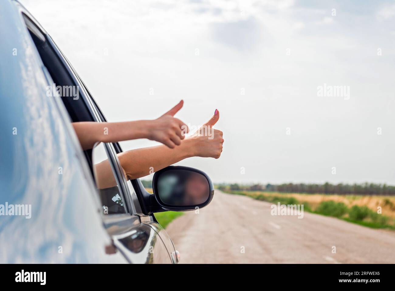 Hands of a woman and kid are showing a thumbs-up sign from car windows ...