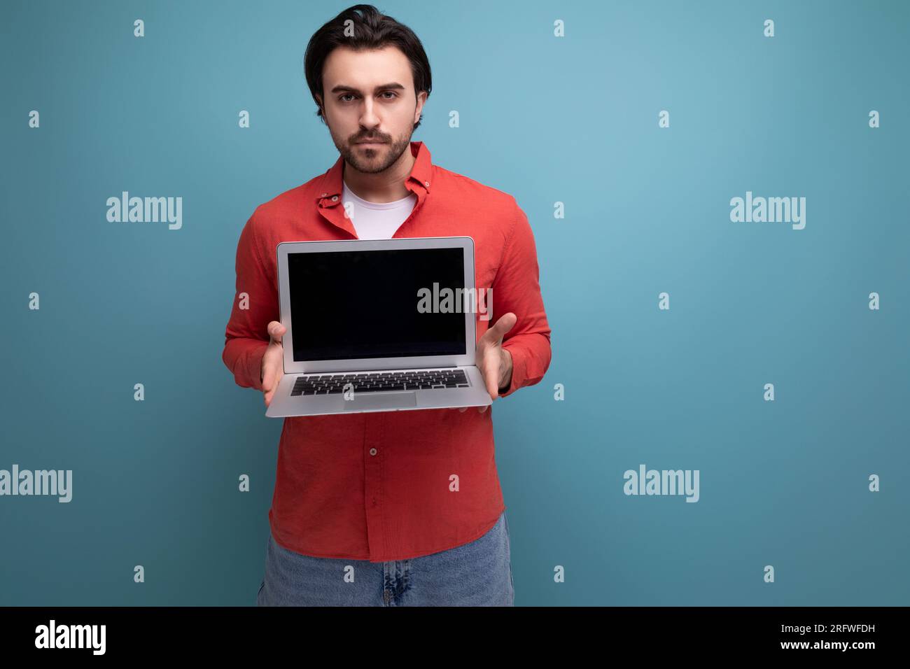 handsome young brunette man showing advertisement on screen with mockup ...
