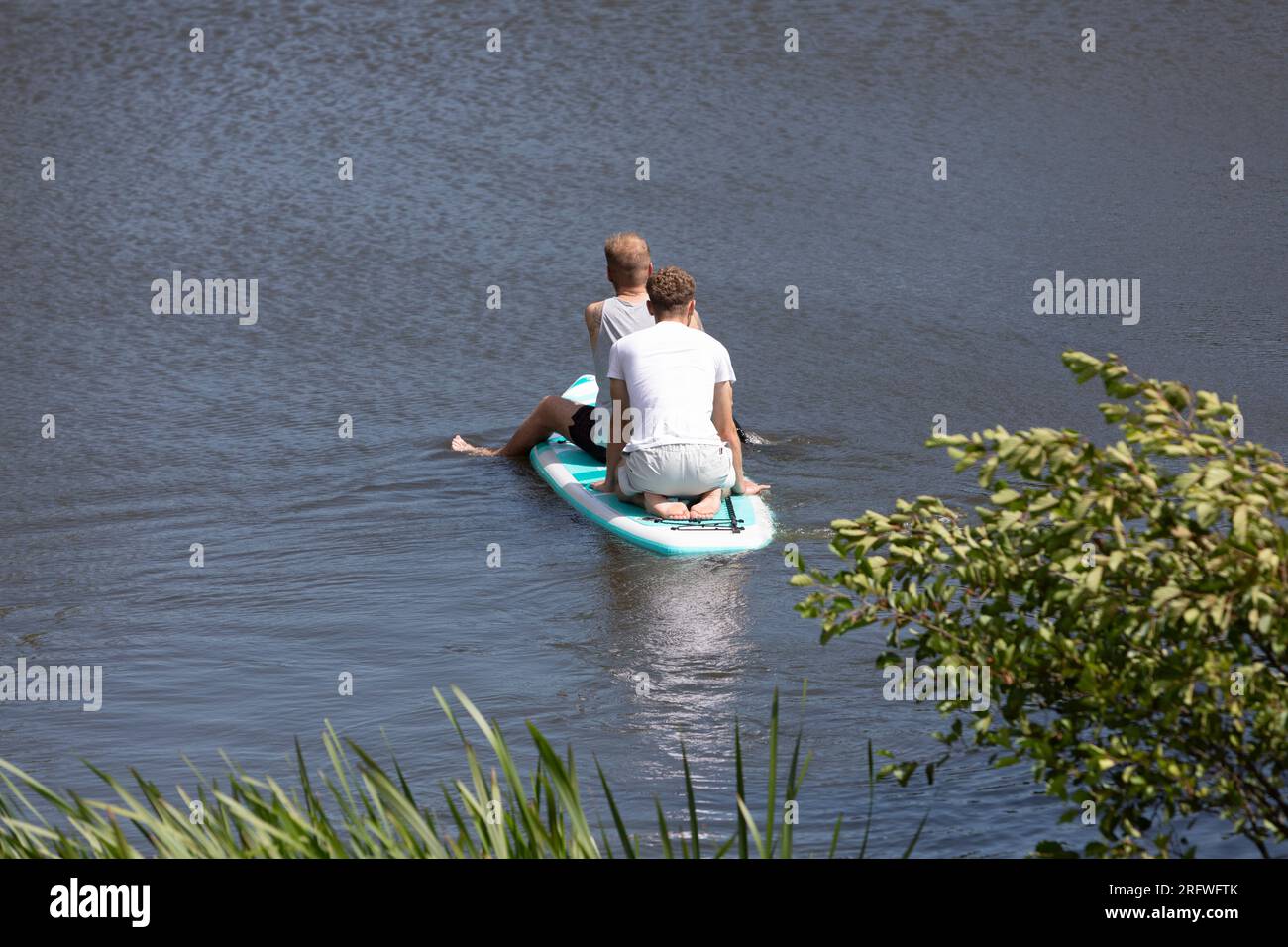 Two young men on a paddle board on a calm canal Stock Photo - Alamy