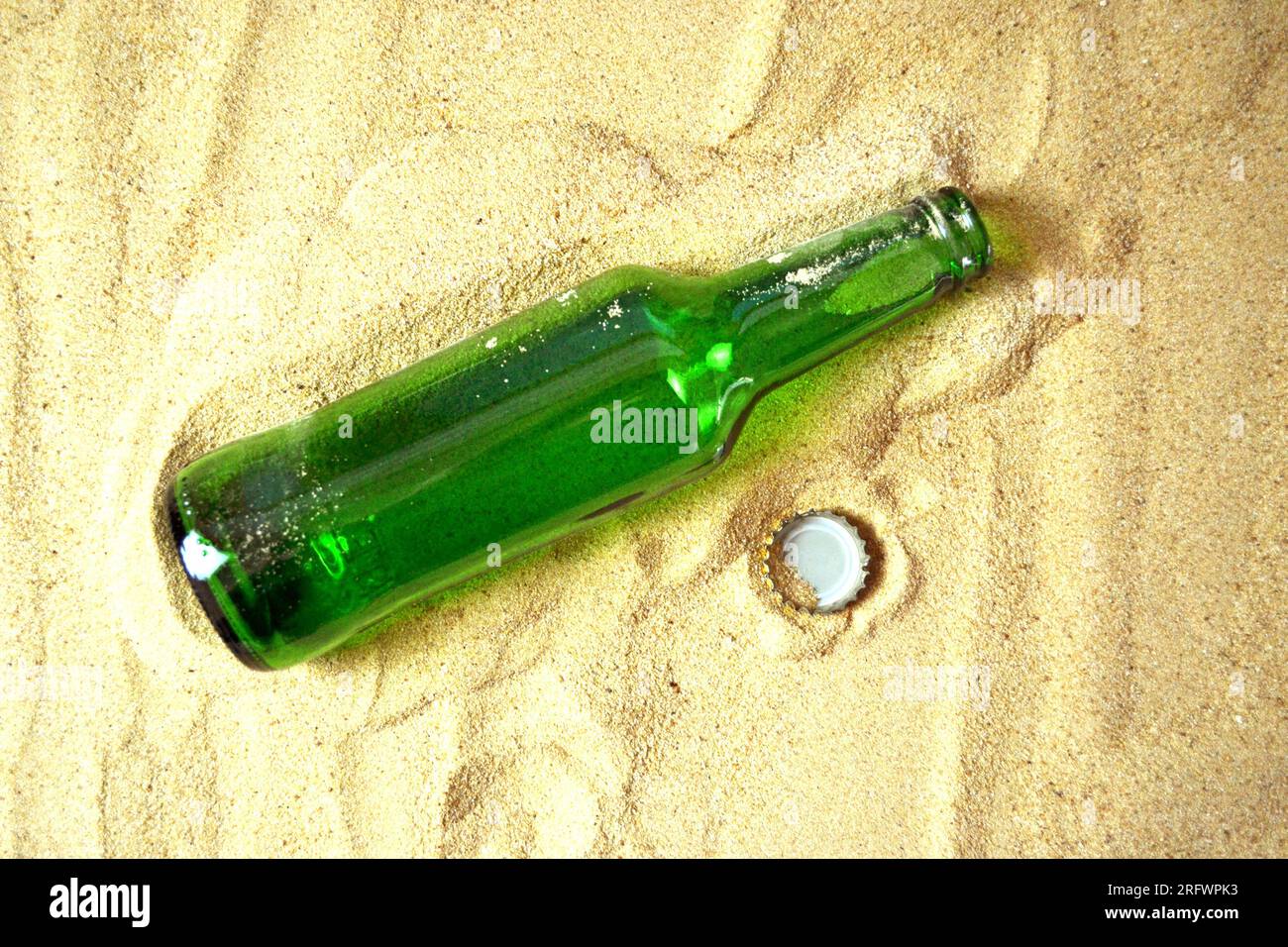 A waste of a drink bottle with a cap thrown on the sand at the beach ...