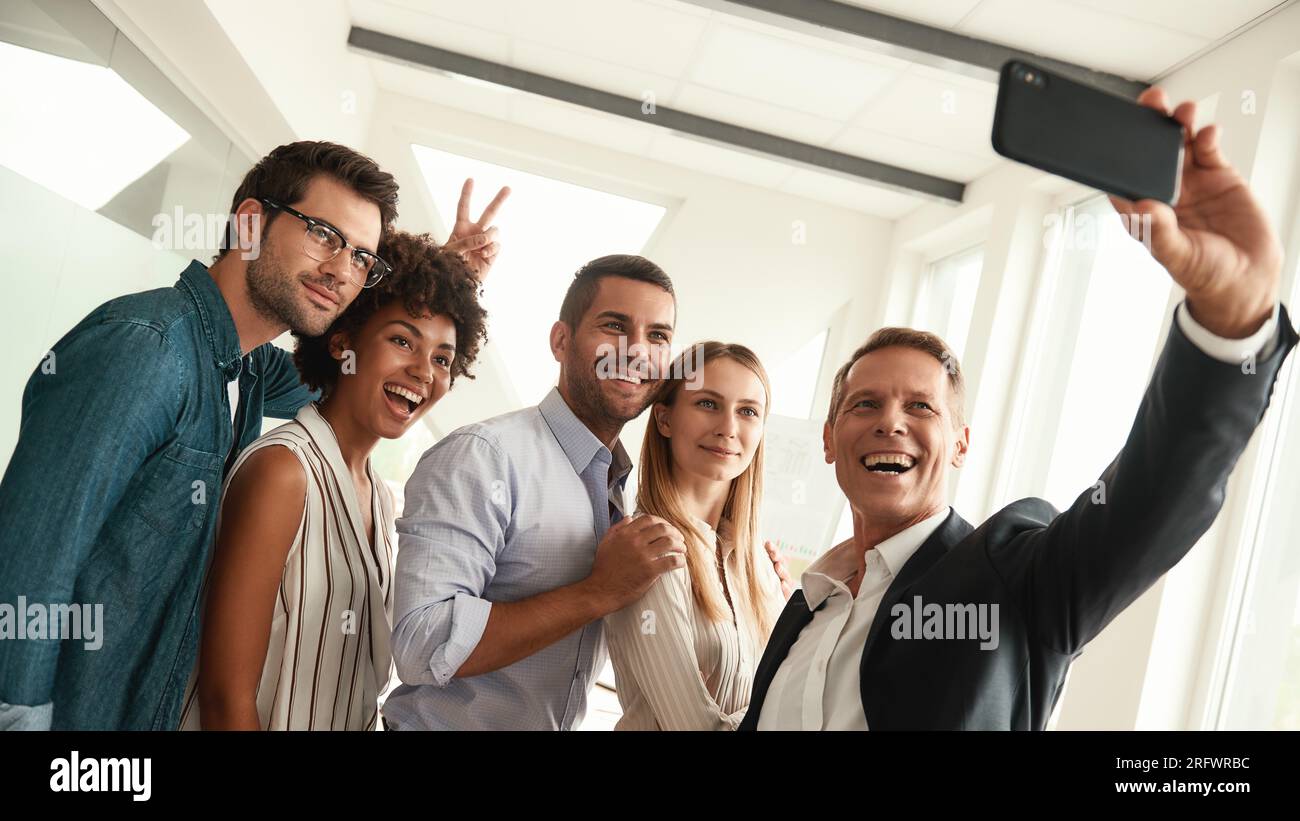 Happy moments. Group of smiling colleagues taking selfie and gesturing ...