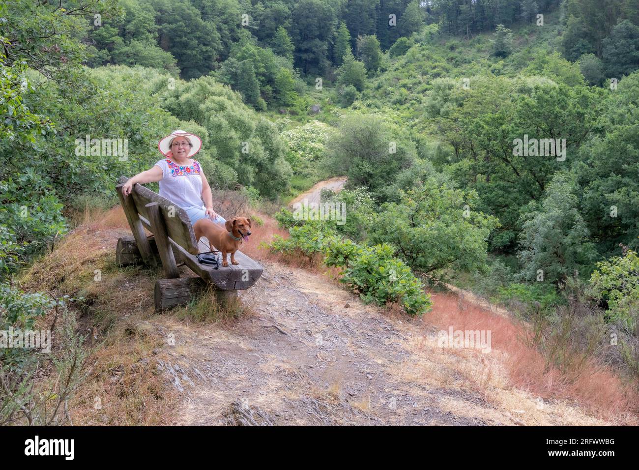 Adult woman sitting with her brown dachshund on top of a mountain in ...