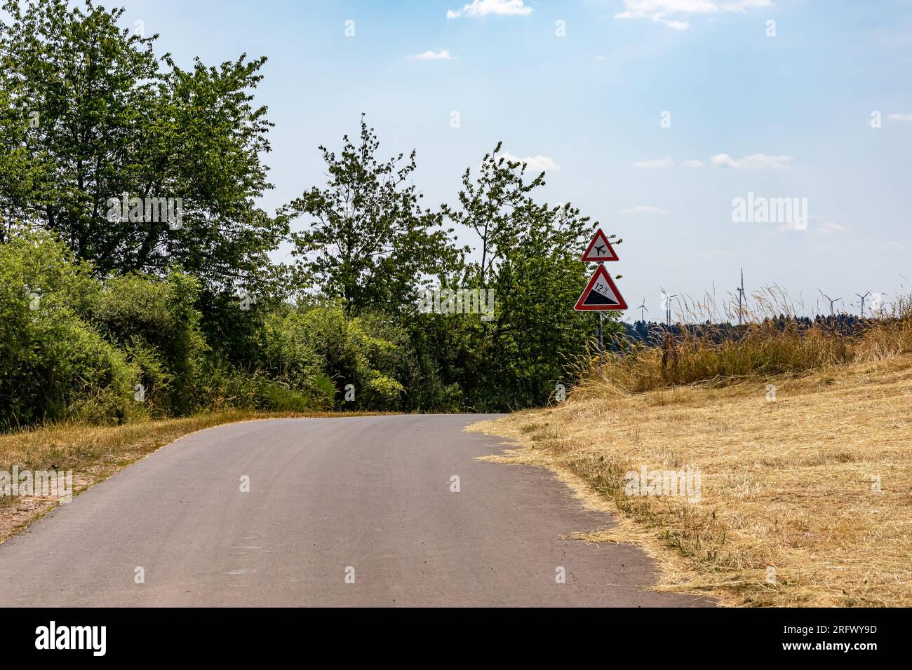 Country road between dry grass and wild vegetation, traffic signs ...
