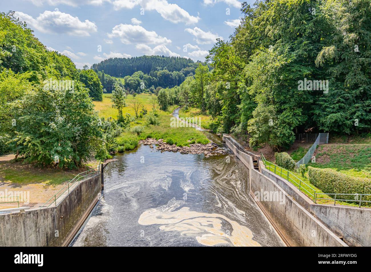 Water flowing from Staumauer Bitburger dam into Prum river, valley and ...
