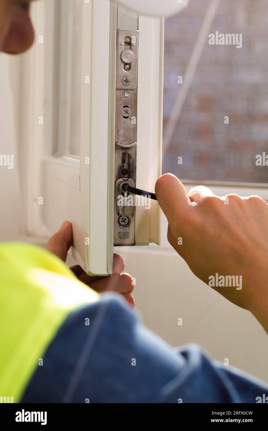The master repairs fittings in a plastic window using a hex key tool ...