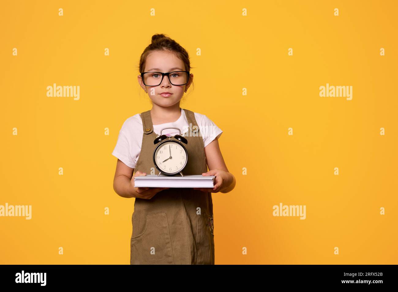 Authentic serious little child girl, primary school student holds a ...