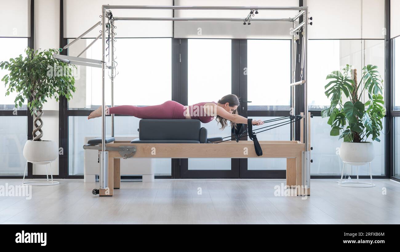 Woman doing pilates exercise on cadillac reformer machine Stock Photo ...