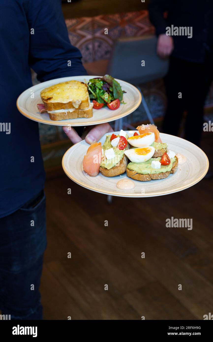 Server bringing out breakfast two dishes, Classic french toast with ...