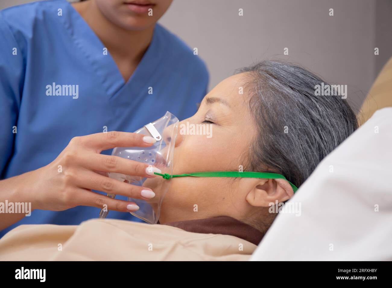 Nurse putting oxygen mask with patient elderly woman on bed for ...