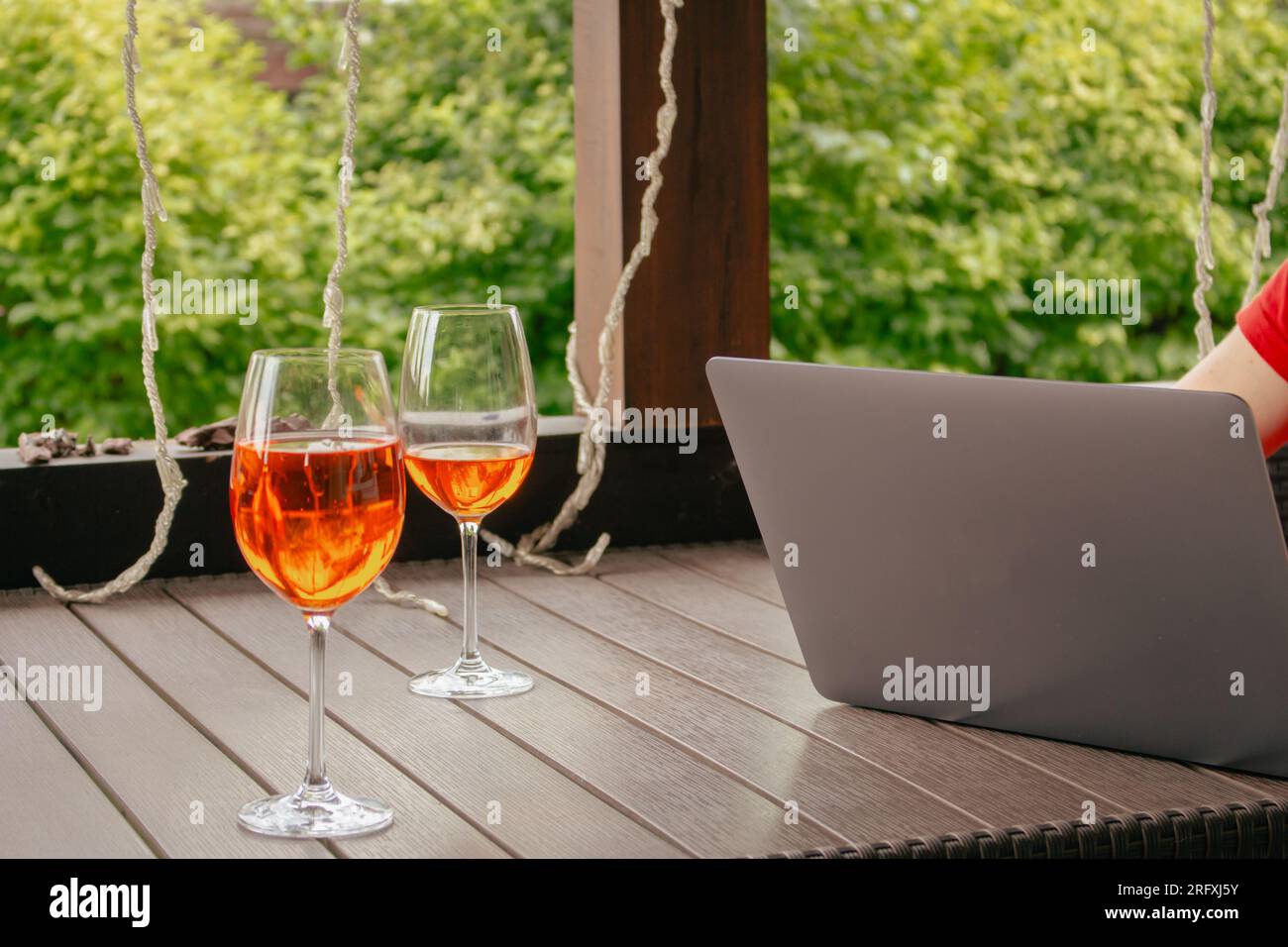 Laptop with glass of Aperol cocktail. Unknown person working on ...