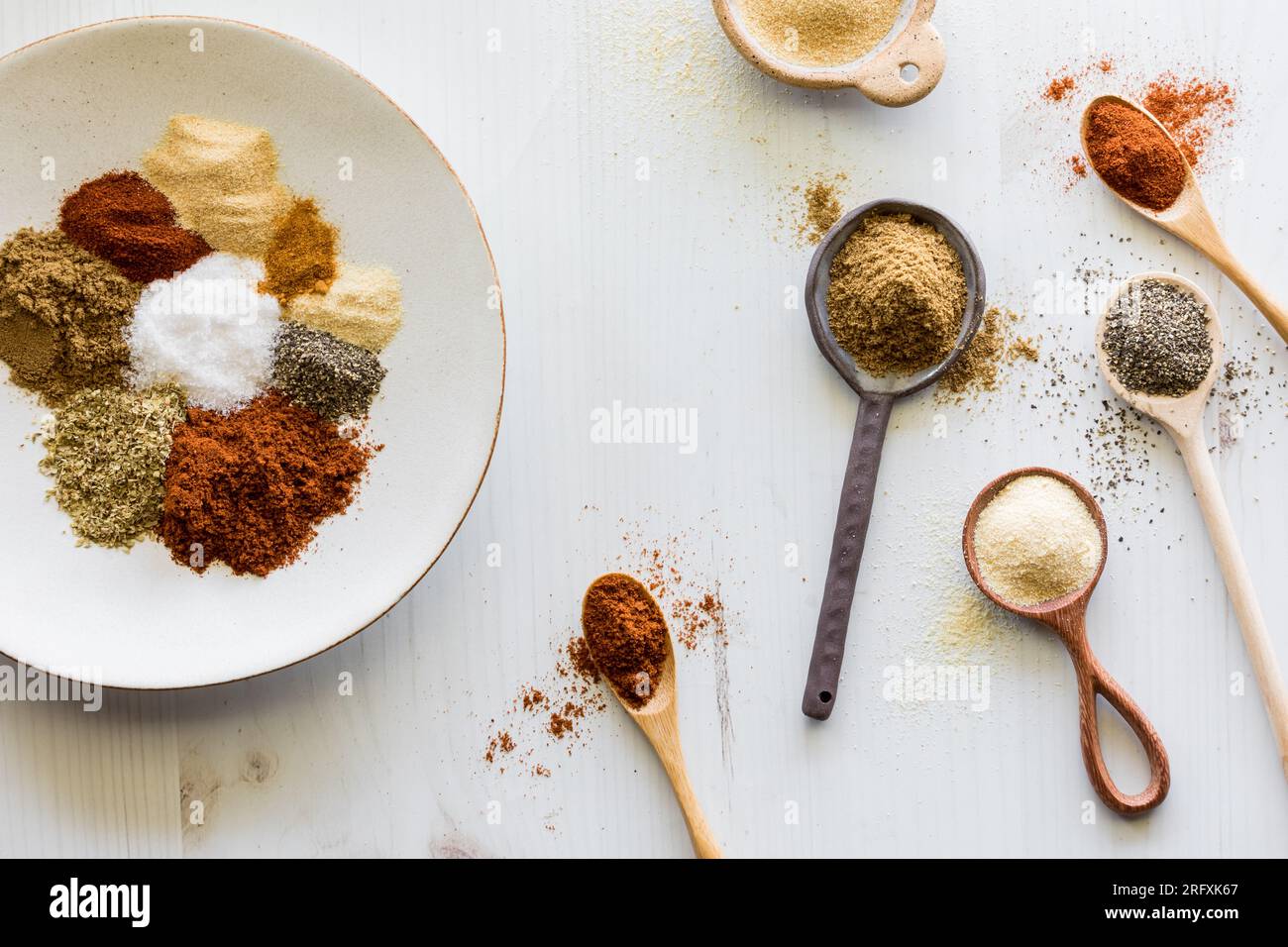 Spoons with messy piles of spices and a piles on a plate with copy ...