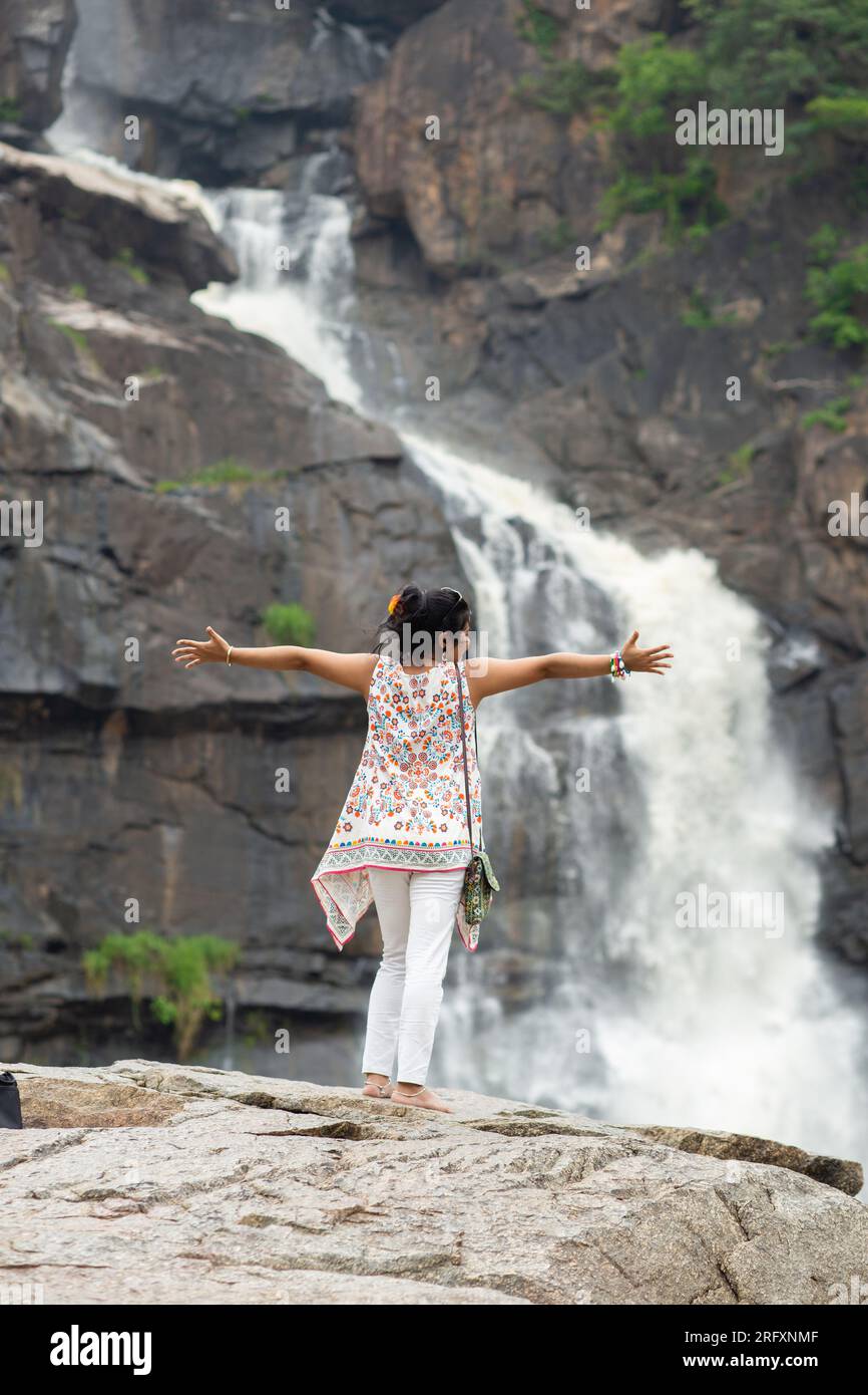 An Indian female girl woman enjoying natural beauty of waterfall with ...