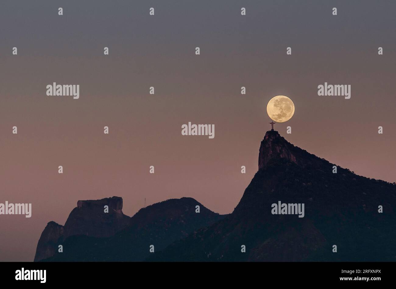 Full moon setting behind Corcovado mountain with Christ the Redeemer ...