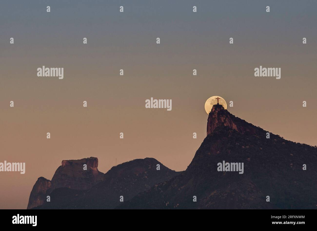 Full moon setting behind Corcovado mountain with Christ the Redeemer ...