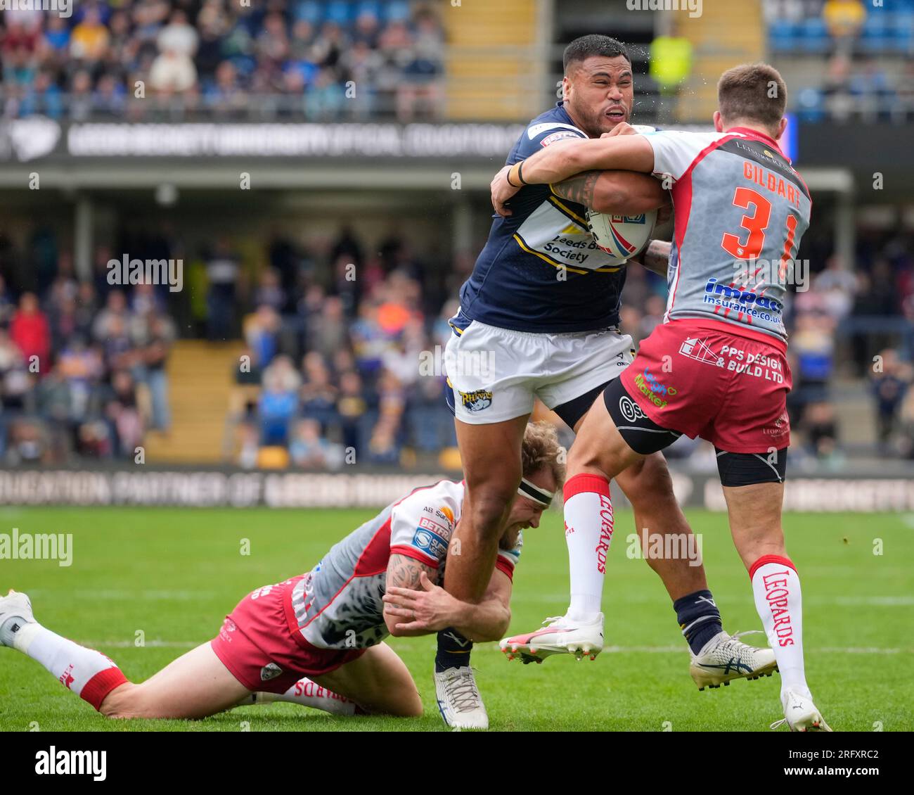 Sam Lisone #15 of Leeds Rhinos runs into Oliver Gildart #31 of Leigh ...