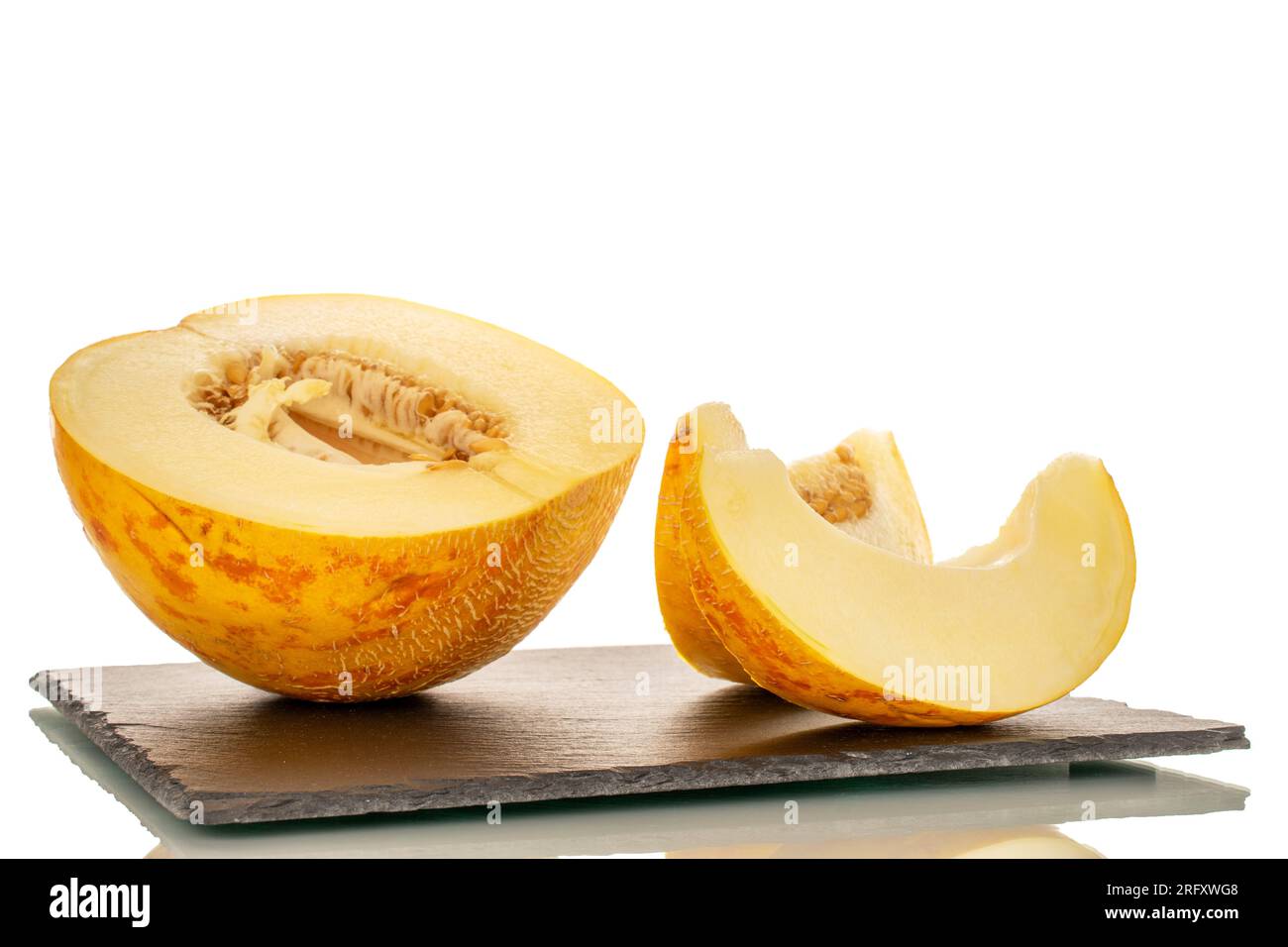 One yellow melon cut into slices on slate stone, macro, isolated on ...