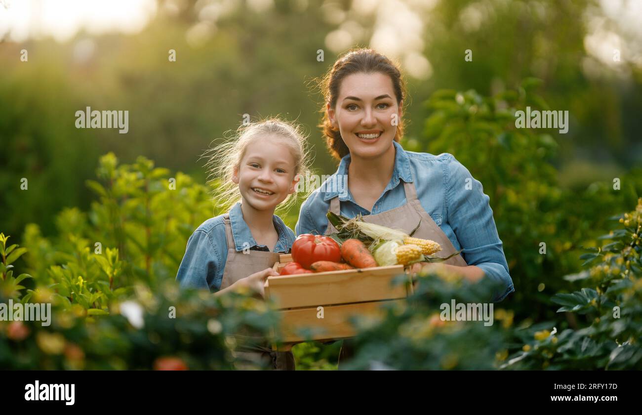 Happy mother and daughter gardening in the backyard organic garden. Kid ...