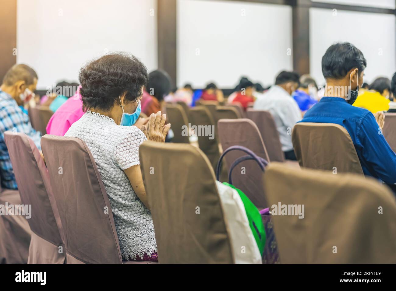 Back view of senior woman wear face mask attending and listening to the ...