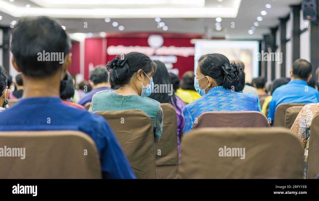 Back view of senior woman wear face mask attending and listening to the ...
