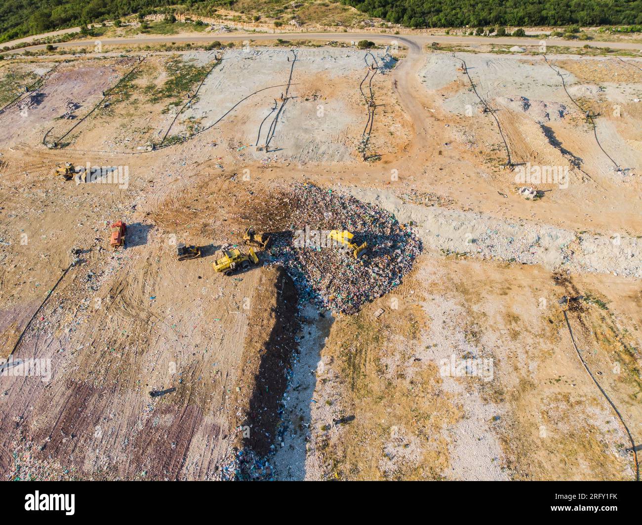 Aerial view from above of dumping site. Garbage trucks. Yellow tractor ...