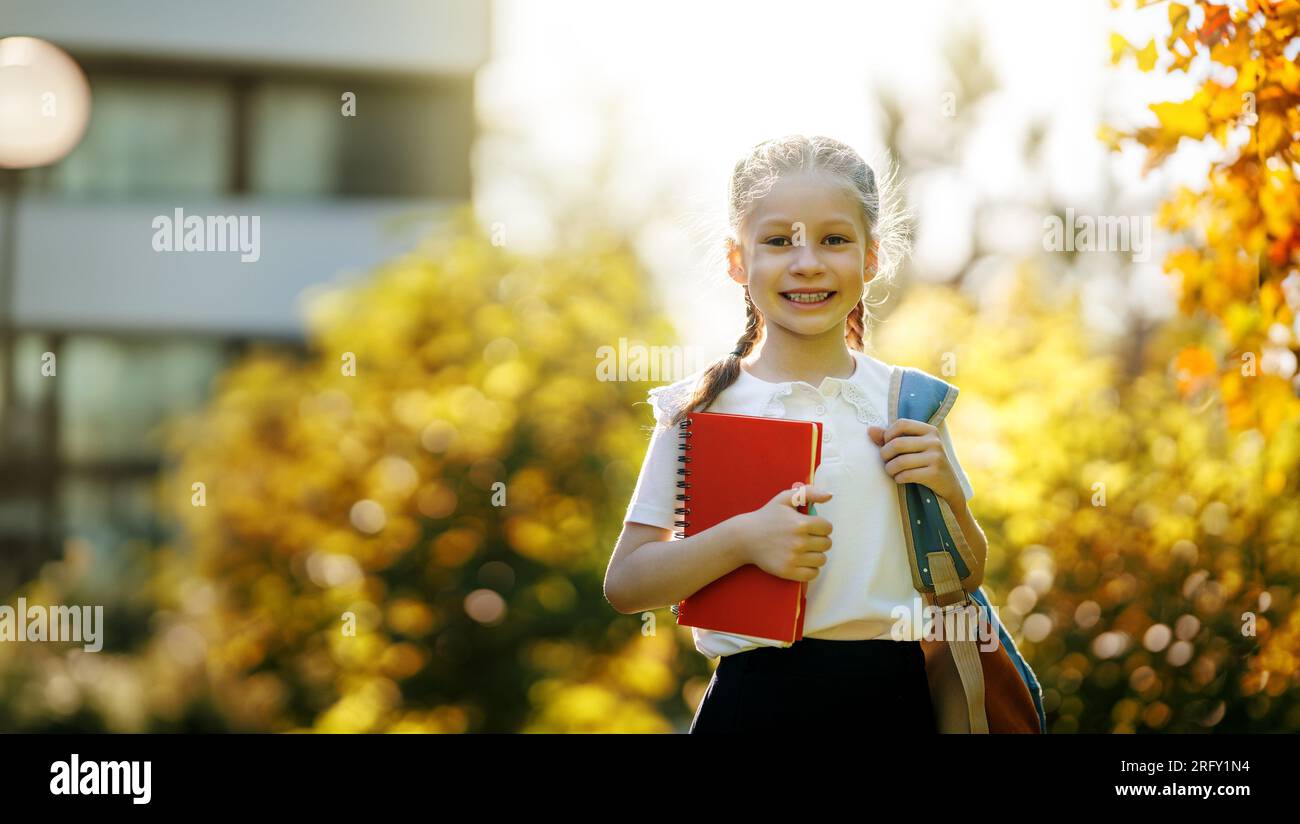 Pupil of primary school. Girl with backpacks outdoors. Beginning of ...