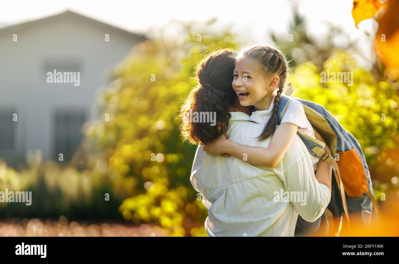 Parent and kid going to school. Woman and girl with backpack behind the ...