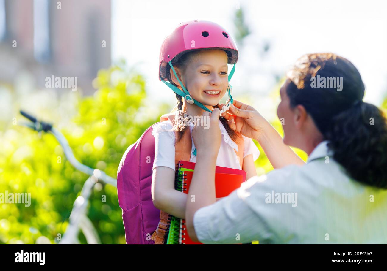 Girl in safety helmet with bike and backpack. Happy child with mother ...