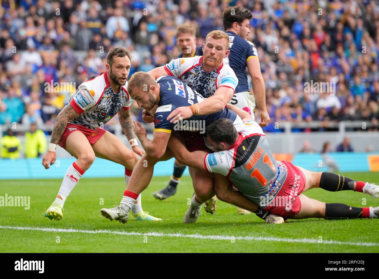 Jarrod O’Connor #14 of Leeds Rhinos drives through the tackle of Joe ...