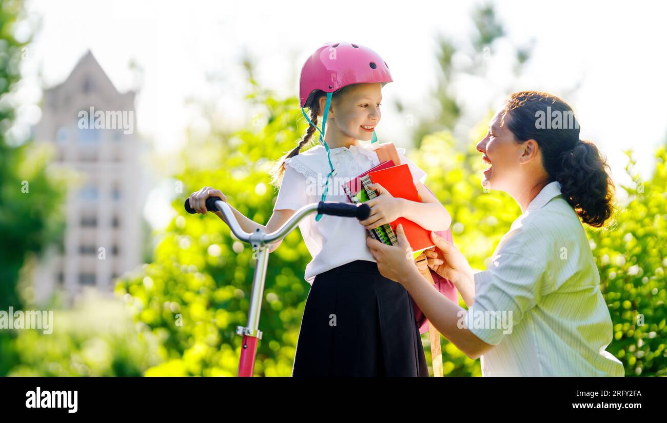 Girl in safety helmet with bike and backpack. Happy child with mother ...