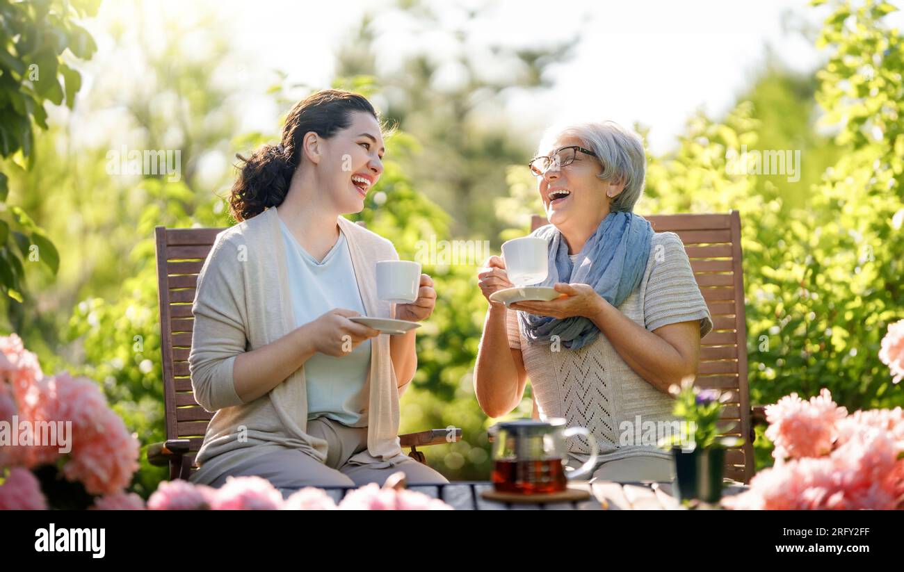 Happy young woman and her mother drinking tea in summer morning. Family ...