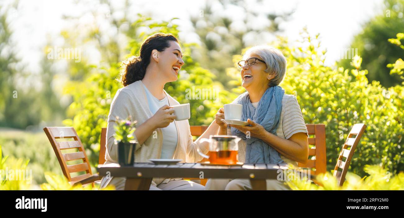 Happy young woman and her mother drinking tea in summer morning. Family ...