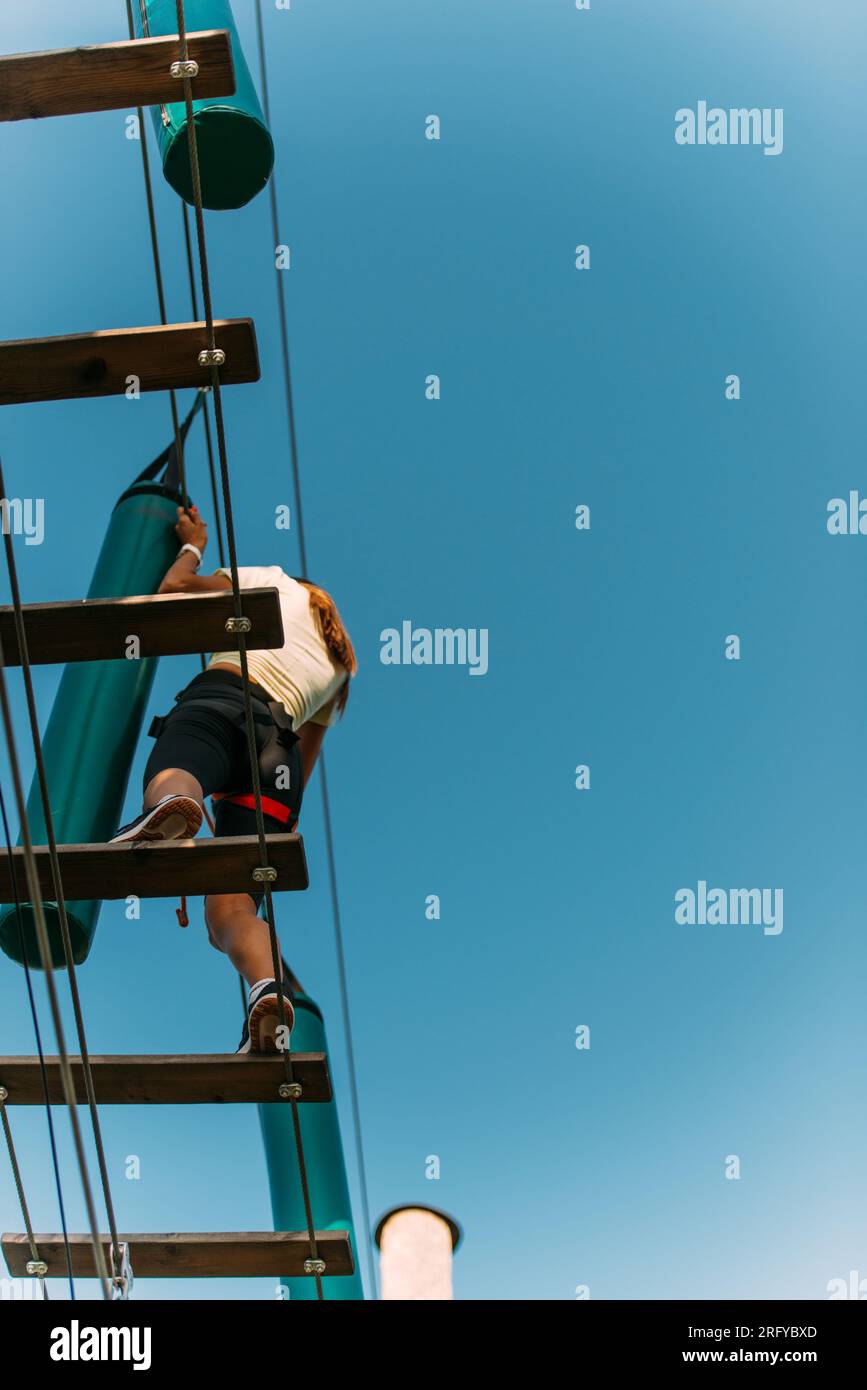 Young professional climber clearing the ladder obstacle with ease in ...